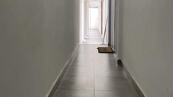 Um corredor comprido e estreito com piso de azulejos e paredes brancas.