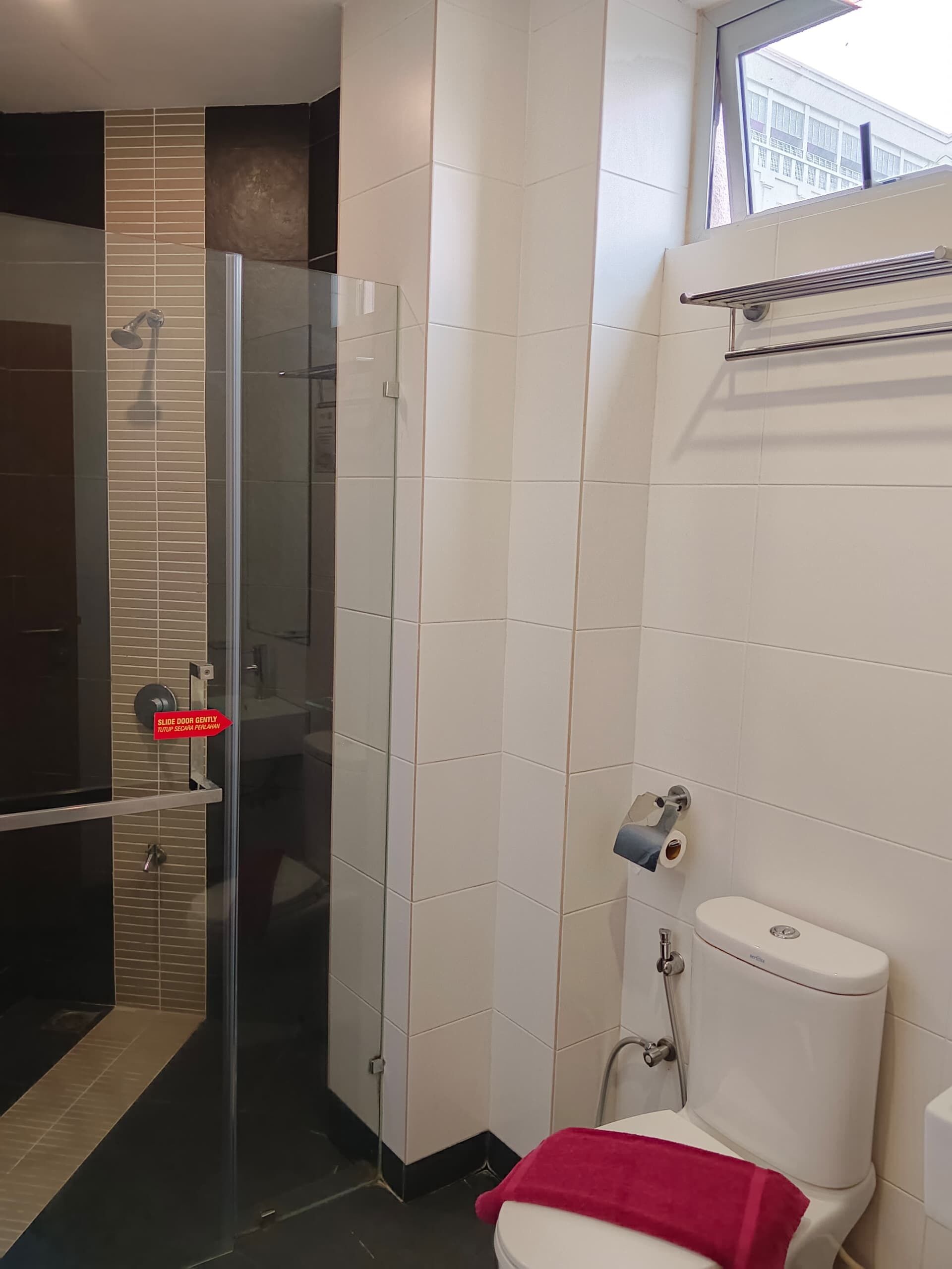 Uma casa de banho moderna com cabine de duche em vidro, sanita e barra de toalhas.