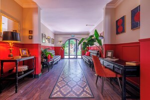 Um corredor com esquema de cores vermelho e branco, piso de madeira e tapete estampado.