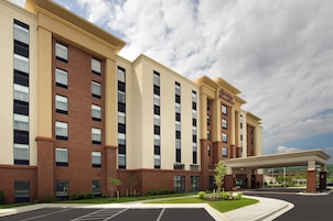 Um hotel Hampton Inn & Suites com fachada de tijolos, grandes janelas e entrada coberta.
