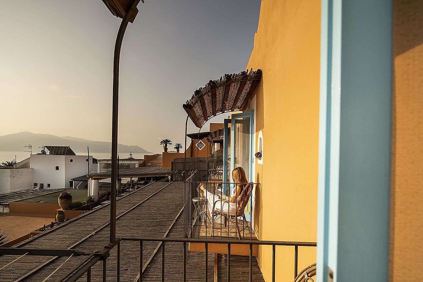 Uma varanda com vista para uma linha de trem e um prédio com porta azul.