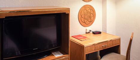 Uma escrivaninha de madeira com uma televisão, uma cadeira e duas peças decorativas na parede.