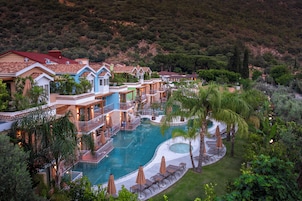 Um resort com uma piscina grande, vários edifícios e muita vegetação.