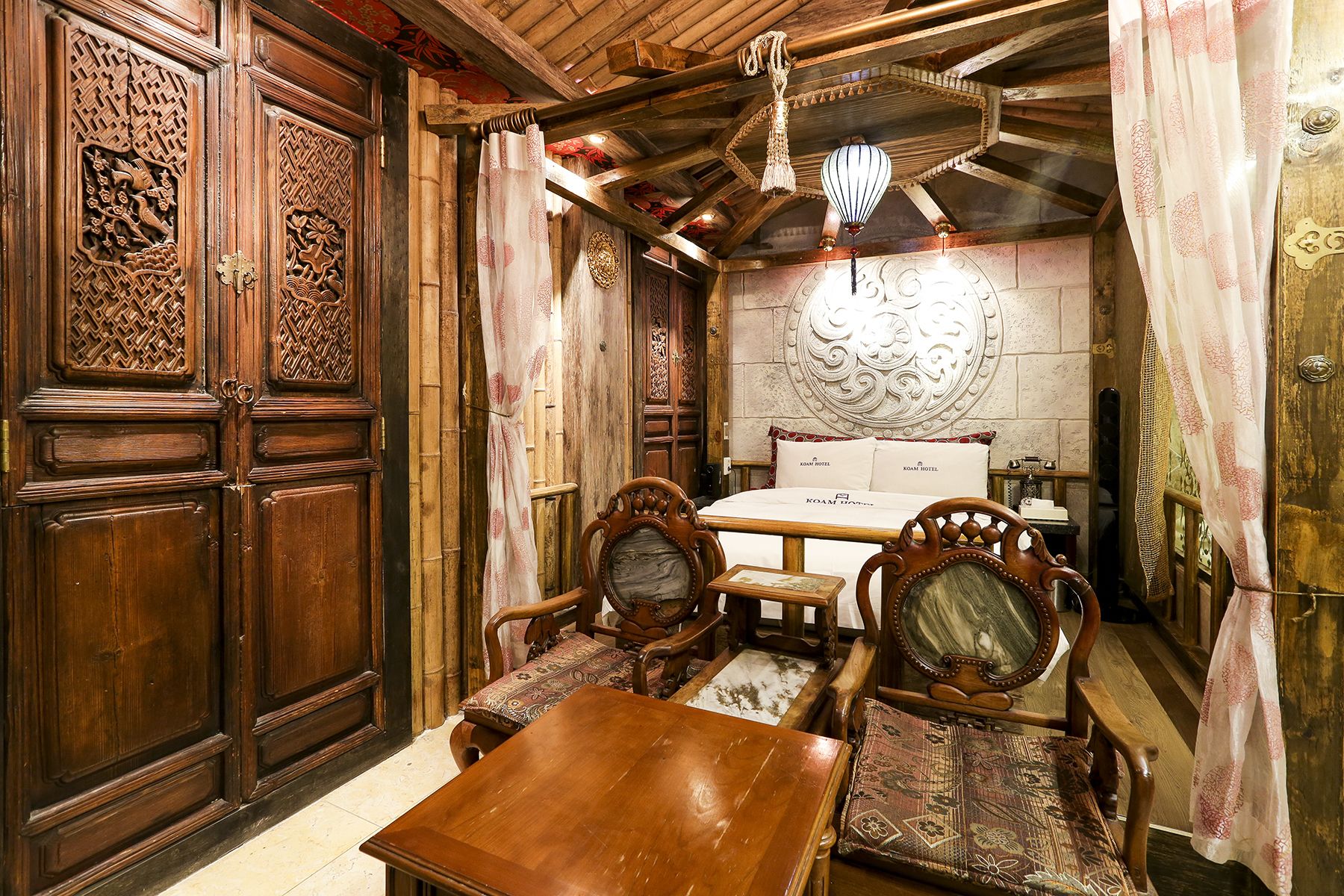 Quarto de madeira tradicional com uma cama, uma mesa e cadeiras.