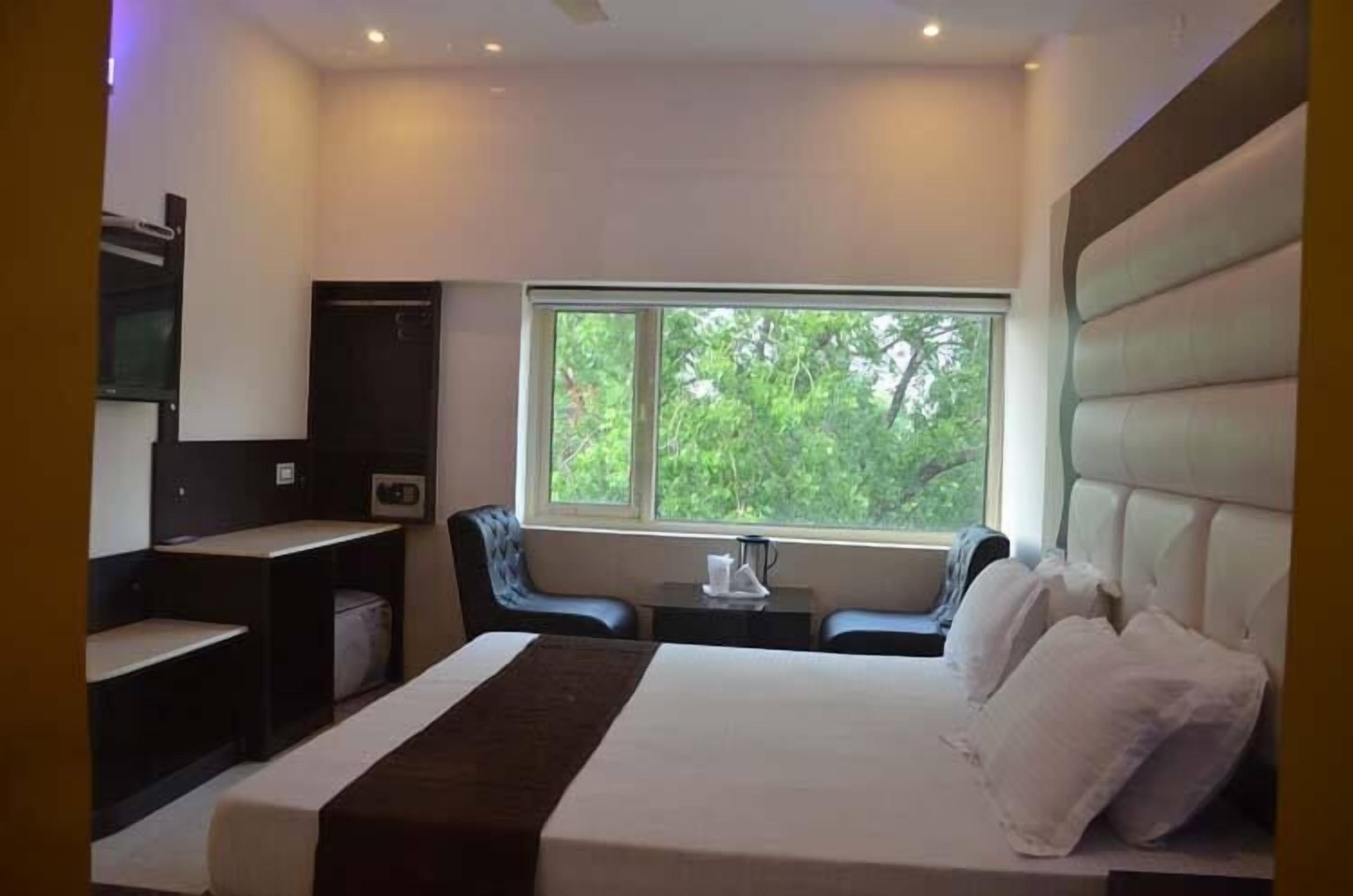 Quarto de hotel moderno com uma cama grande, uma mesa e uma cadeira.