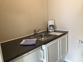 Uma cozinha com pia, cafeteira e um caderno sobre o balcão.