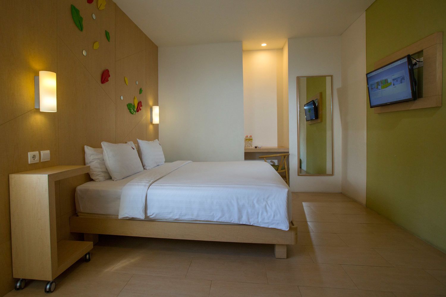Quarto de hotel moderno com uma cama grande, uma escrivaninha e uma televisão.
