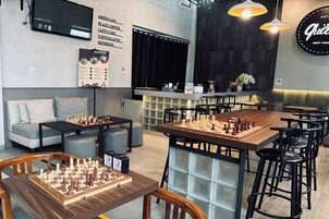 Uma cafeteria moderna com mesas de xadrez, um espaço de bar e um quadro de cardápio.