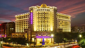 Um hotel de vários andares com uma entrada imponente e uma grande placa iluminada.
