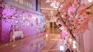Um hall amplo com piso de madeira polida, um arranjo floral rosa e quadros nas paredes.