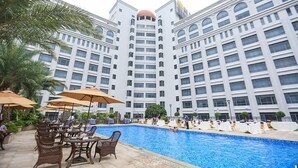 Um hotel com uma piscina grande, área de estar externa e fachada de edifício moderna.