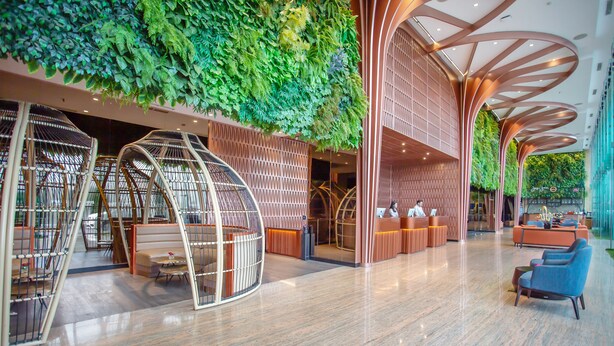 Um lobby moderno com parede verde, áreas de estar e balcão de recepção.