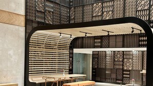 Um interior moderno com parede estampada em padrão geométrico, móveis de madeira e um banco.