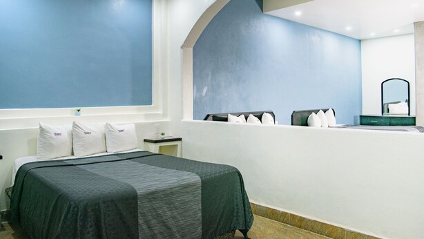 Quarto de hotel com cama, mesa de cabeceira, espelho e vista para o exterior.