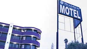 Um motel com uma placa grande, vários andares e um estacionamento cheio de carros.