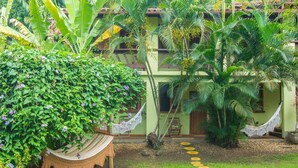 Um jardim exuberante com uma rede, um caminho e um edifício com varanda.