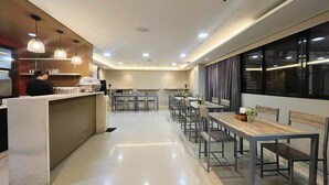 Uma sala de jantar moderna com ilha central, várias mesas e iluminação pendente.