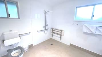 Casa de banho com sanita, chuveiro e janela.