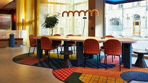 Uma sala de reunião moderna com uma mesa grande, cadeiras e um vaso de planta.