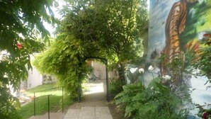 Caminho que serpenteia por um jardim, com um mural à direita.