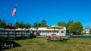 Um motel VINDEL com mesa de piquenique e guarda-sol, cercado por uma vedação e árvores.