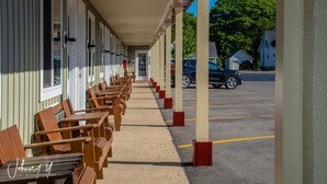 Um motel com fileiras de cadeiras e mesas de madeira sob uma galeria coberta.