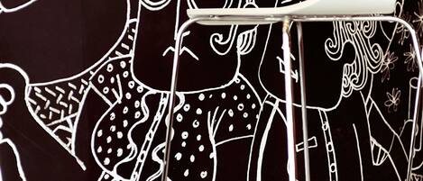 Close-up de um guarda-corpo de metal com fundo preto e desenhos em linha branca de pessoas e padrões abstratos.