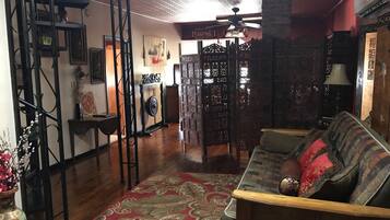 Uma sala de estar aconchegante com um tapete estampado, um sofá com almofadas decorativas, uma mesa de centro de madeira e um portão decorativo.