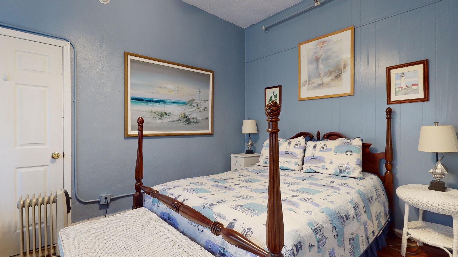 Quarto com cama de dossel, radiador branco e cadeira de vime branca.