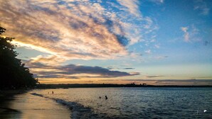 Cena de praia com águas calmas e céu ao entardecer.