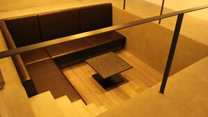 Um interior moderno com um sofá de couro preto, uma pequena mesa de madeira e um corrimão de metal.