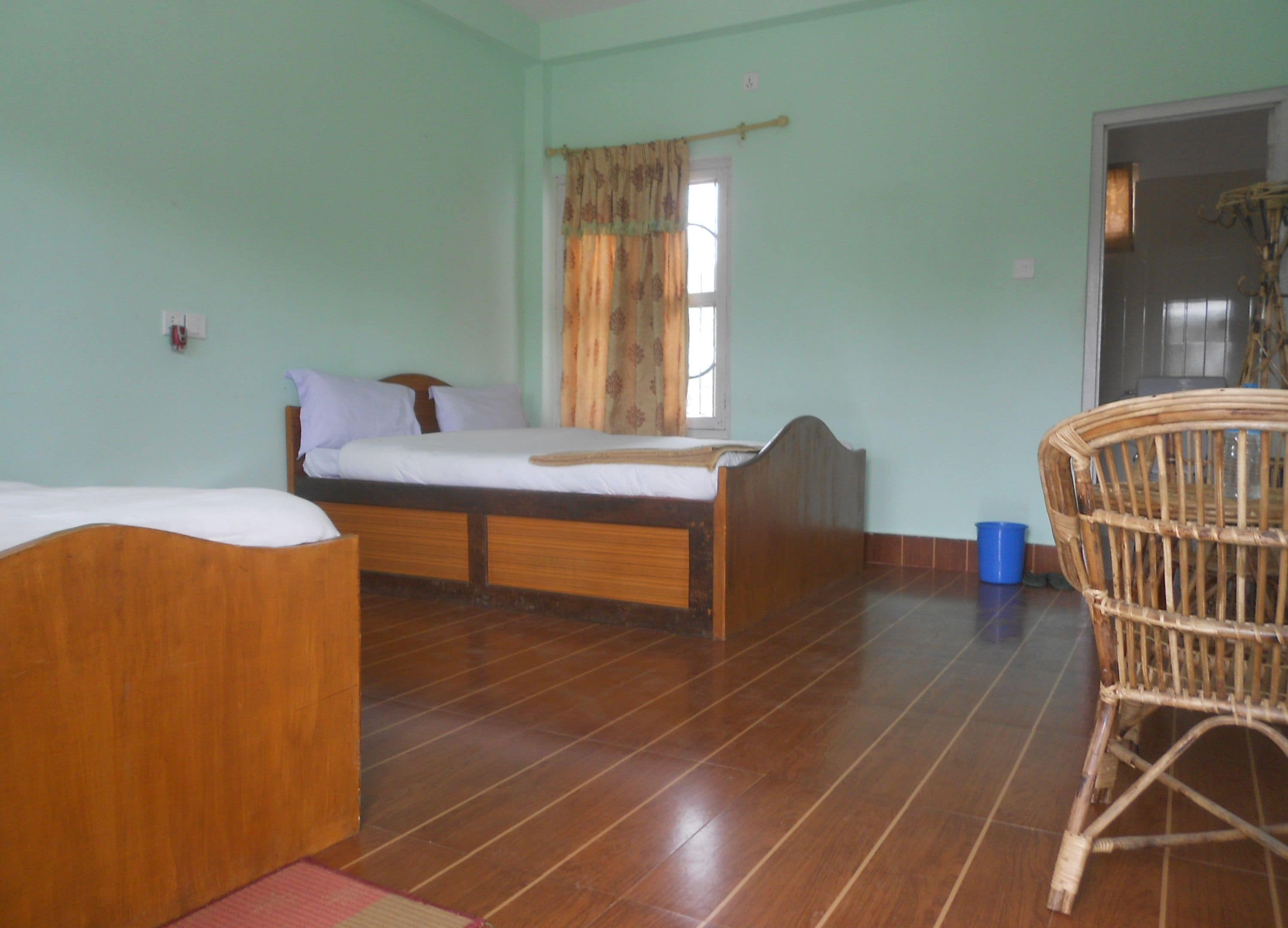 Um quarto com uma cama, uma cadeira e uma janela com cortinas.