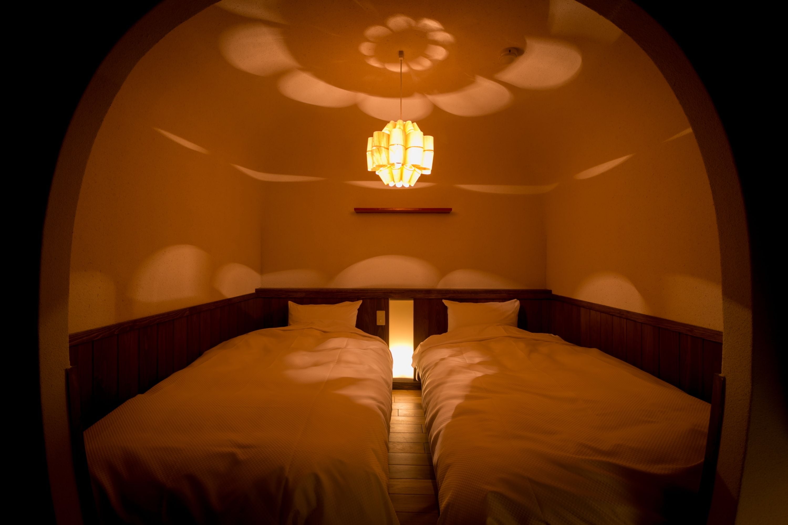 Um quarto aconchegante com duas camas, um candelabro e teto de madeira.