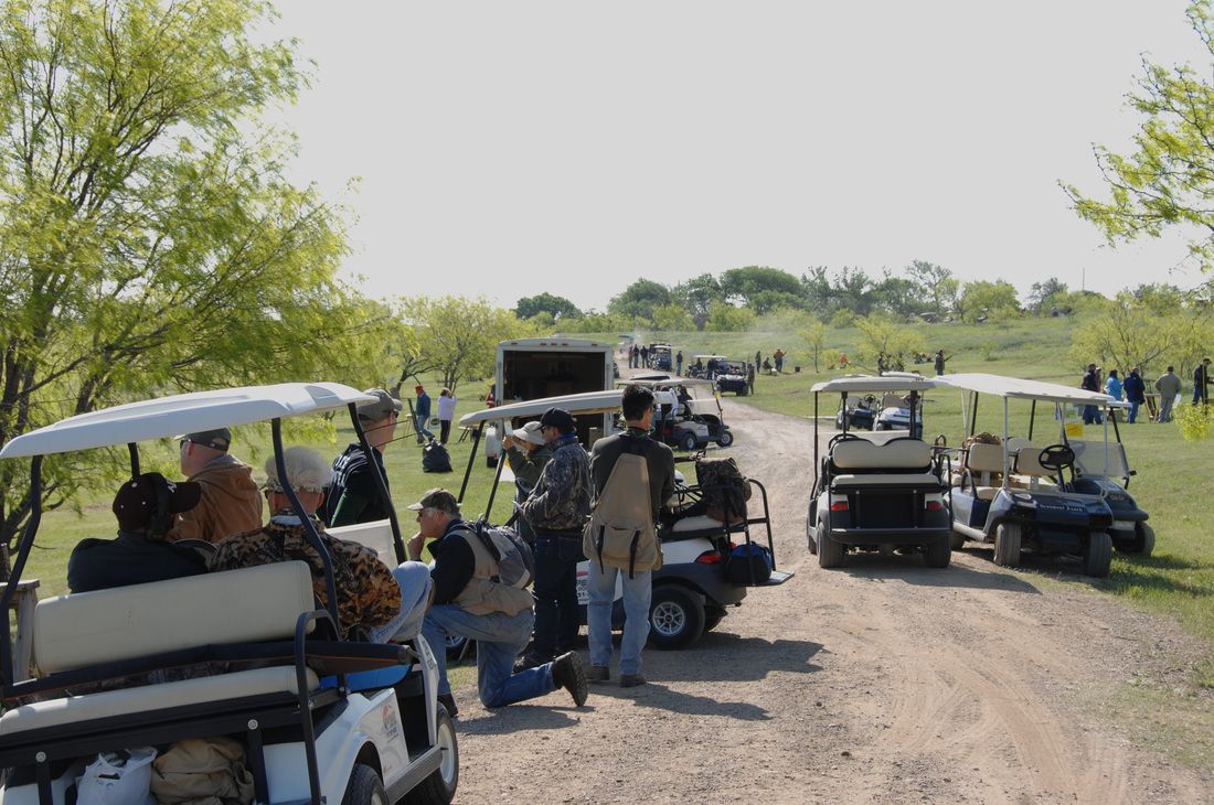 Um grupo de carrinhos de golfe em uma estrada de terra, com pessoas por perto.