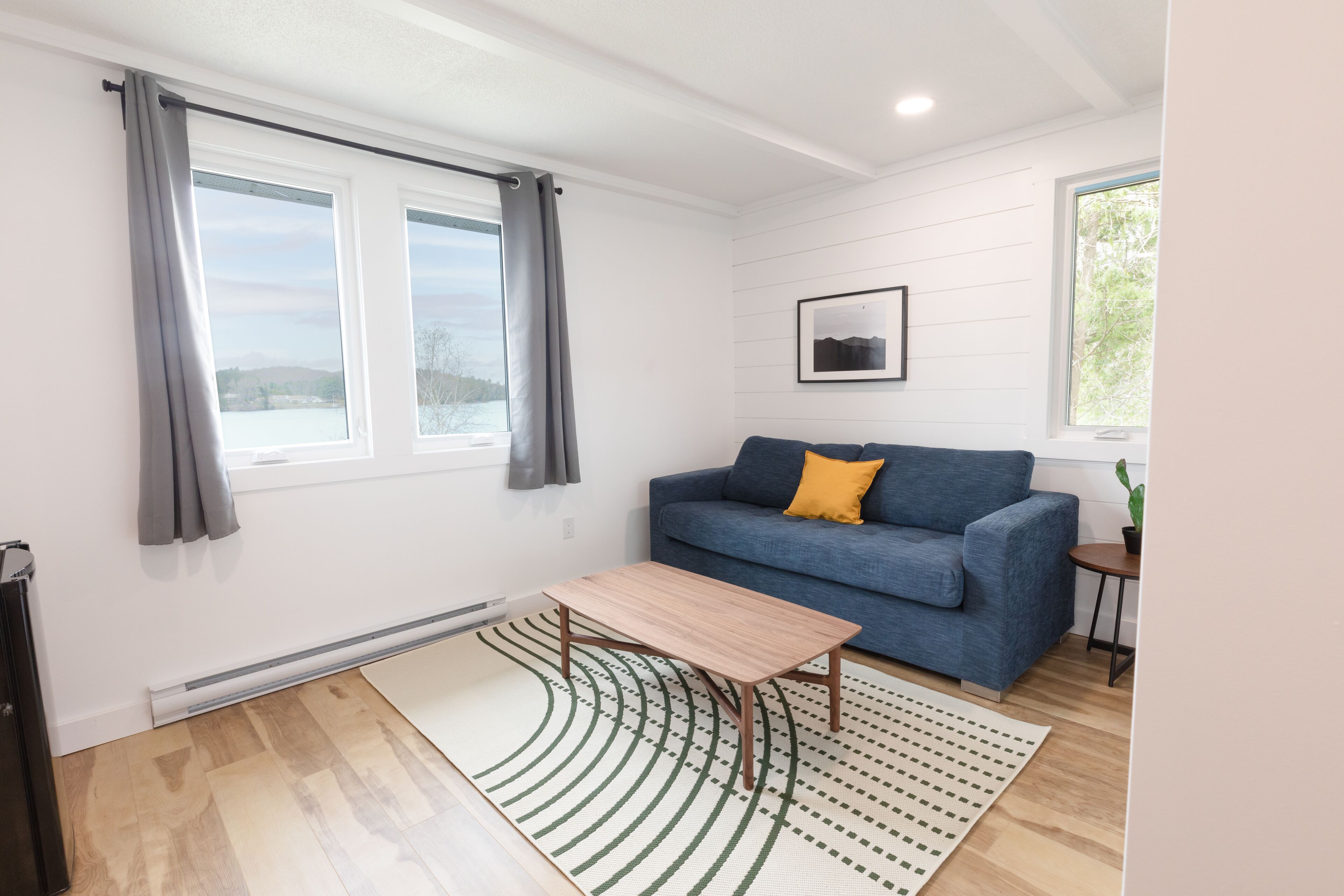 Uma sala de estar moderna com um sofá azul, uma mesa de centro de madeira e um tapete estampado.