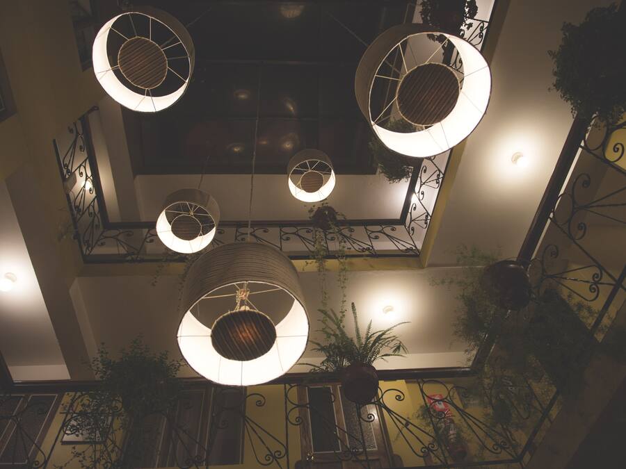 Um átrio de vários níveis com luminárias circulares penduradas e grades de ferro forjado.