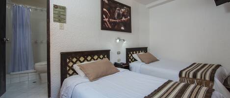 Quarto de hotel com duas camas, chuveiro e uma moldura na parede.
