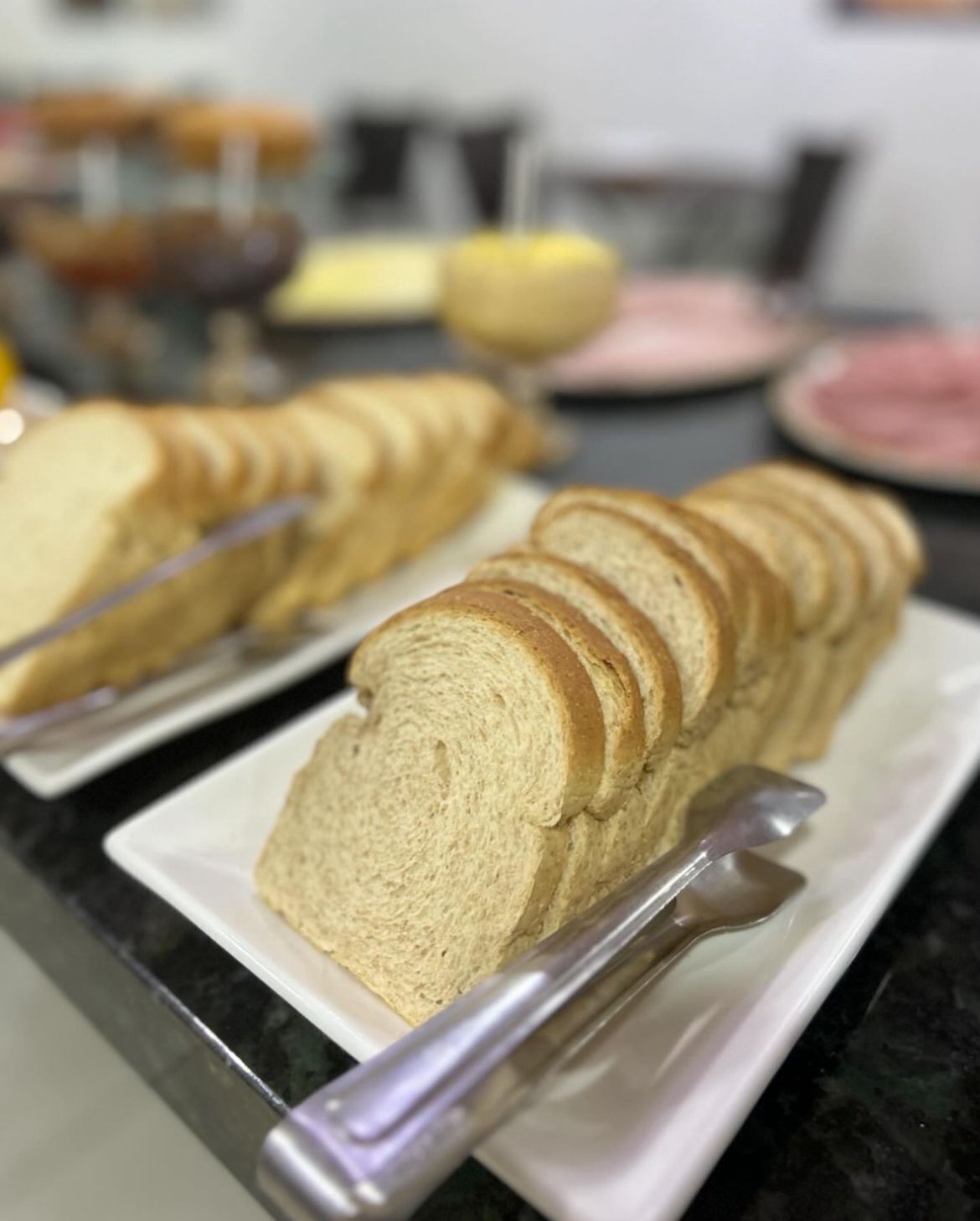 Uma fatia de pão num prato branco com uma faca.