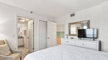 Um quarto com uma cama grande, uma televisão sobre um aparador e uma cadeira.
