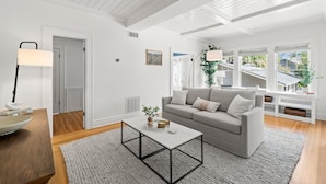 Uma sala de estar moderna com um sofá cinzento, uma mesa de centro branca e uma luminária.