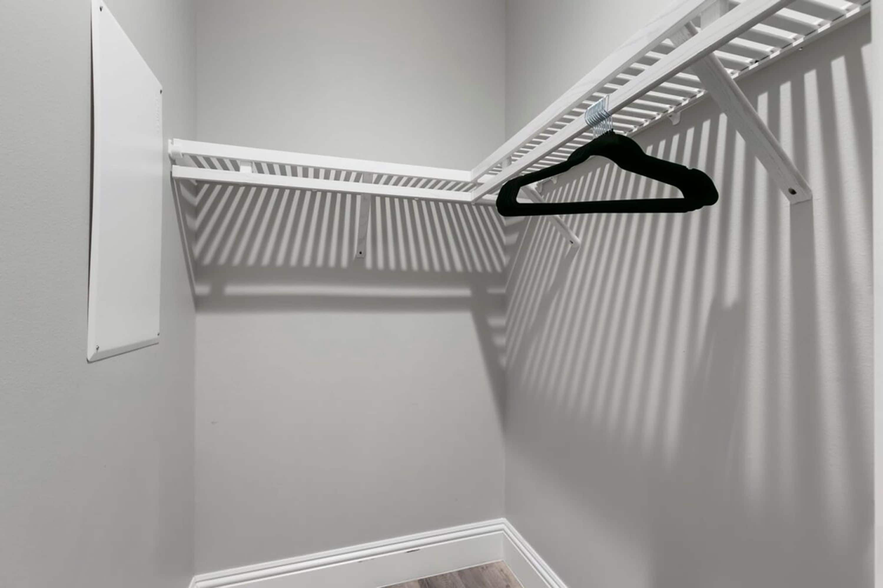 Um canto do quarto com um armário branco e um cabideiro.