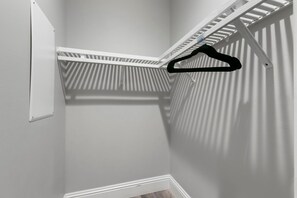 Um canto do quarto com um armário branco e um cabideiro.