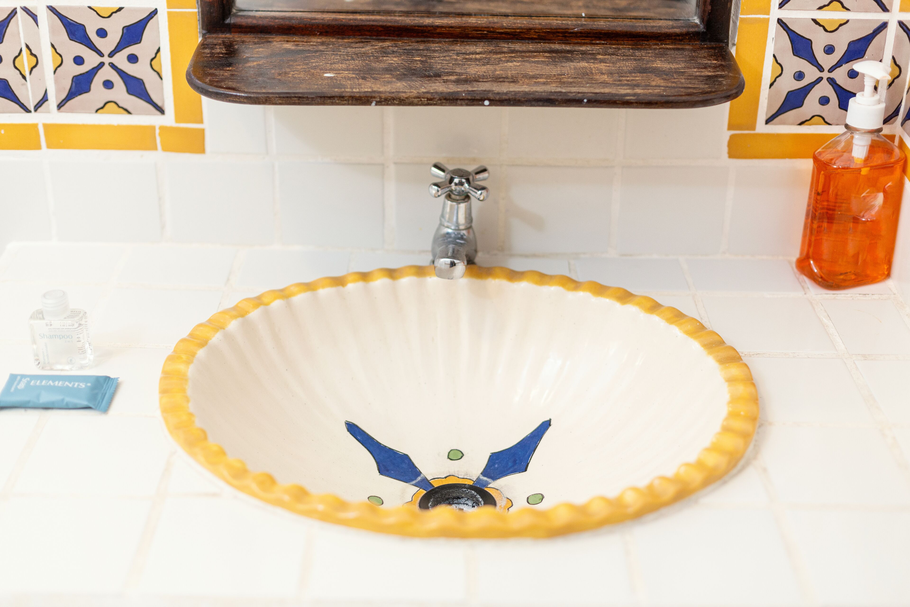 Uma pia de banheiro com um recipiente decorativo, uma torneira e um dispensador de sabonete.