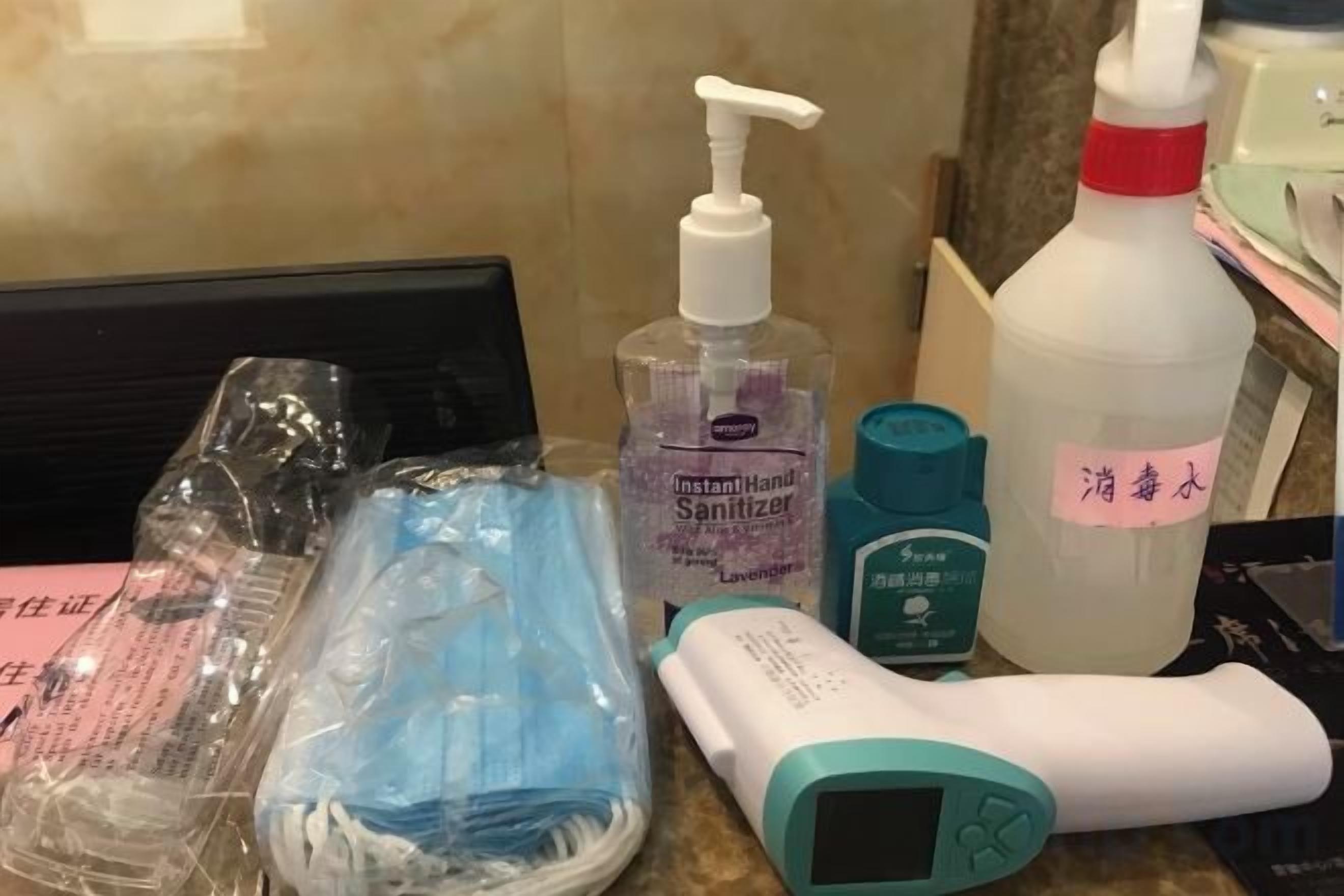 Um balcão com diversos produtos de higiene, incluindo álcool em gel, máscara facial e um frasco de sabonete líquido.