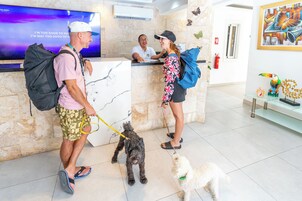 Área de recepção com parede de mármore, tela digital exibindo uma mensagem e balcão de atendimento.
