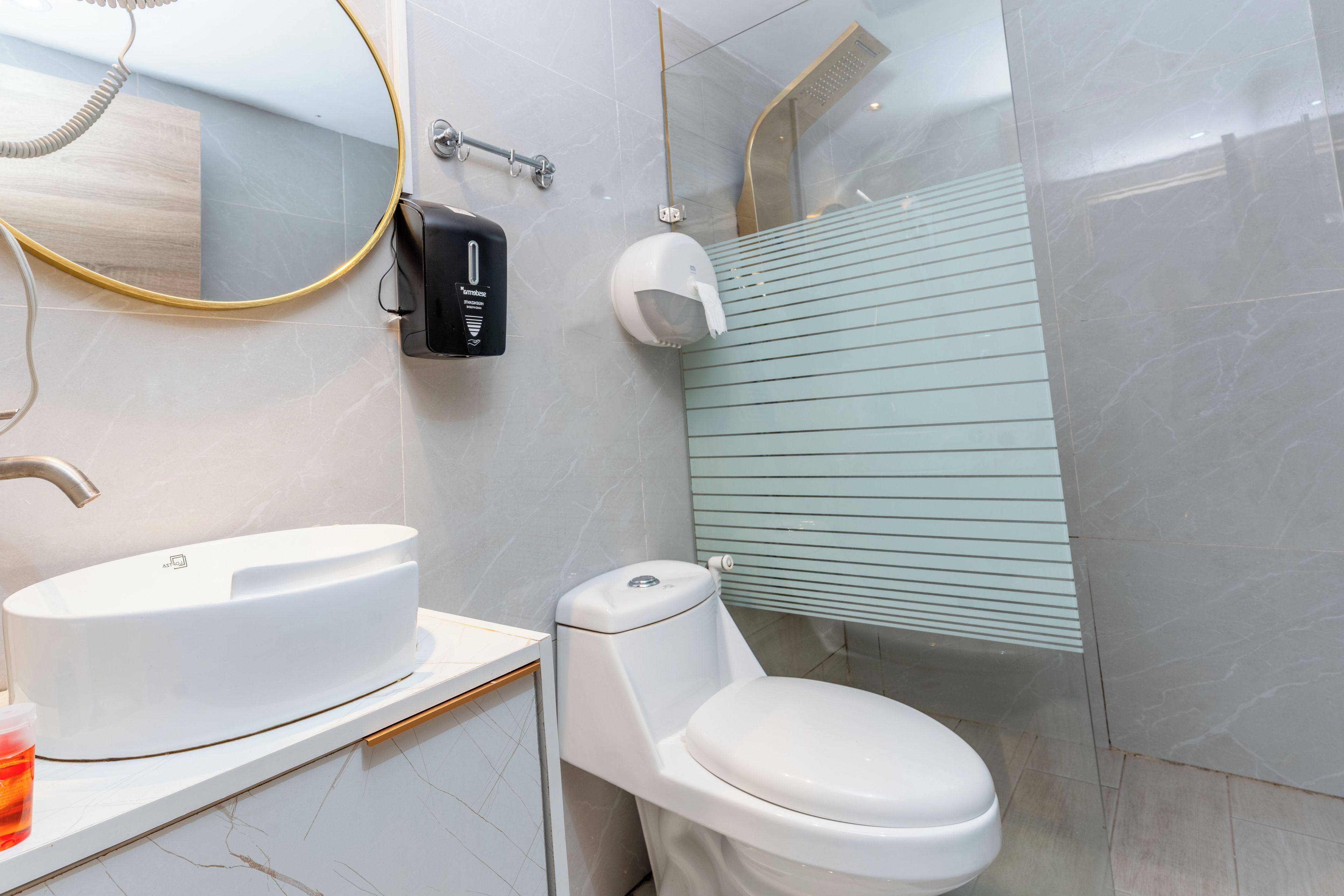 Casa de banho moderna com lavatório, sanita e chuveiro, todos em branco.