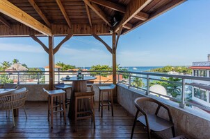 Um deck de madeira com área de estar ao ar livre, com vista para um porto e o mar.