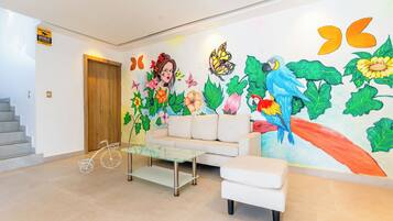 Um lobby moderno com um mural, um sofá, uma mesa de centro de vidro e uma bicicleta.