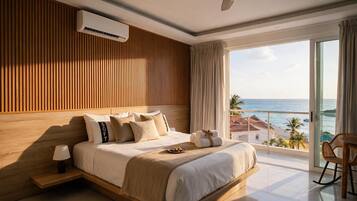 Quarto moderno com uma cama grande, um ventilador de teto e vista para o oceano.