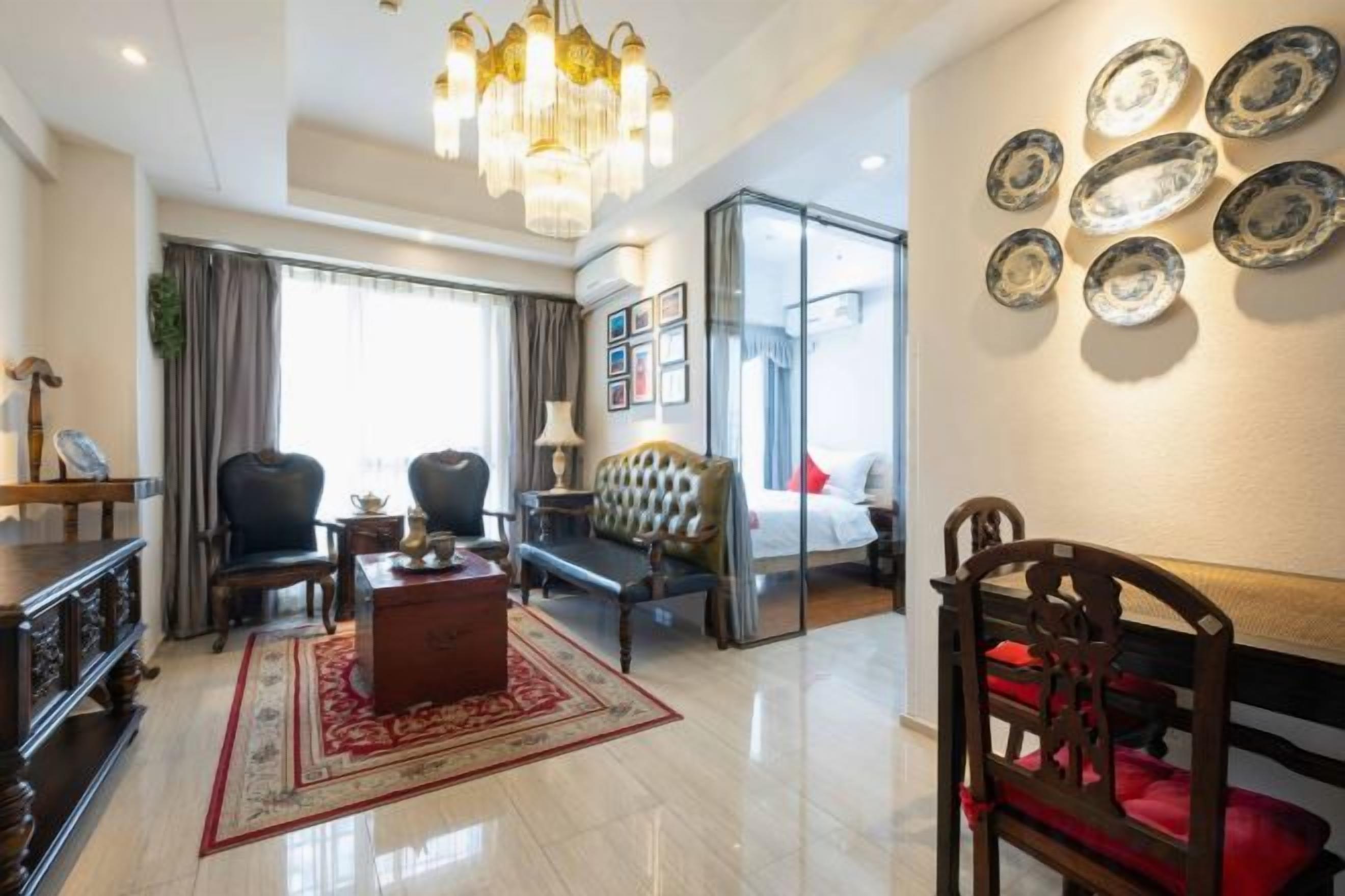 Uma sala de estar bem iluminada com um candelabro, um sofá, uma mesa de centro e um espaço de jantar com mesa e cadeiras.